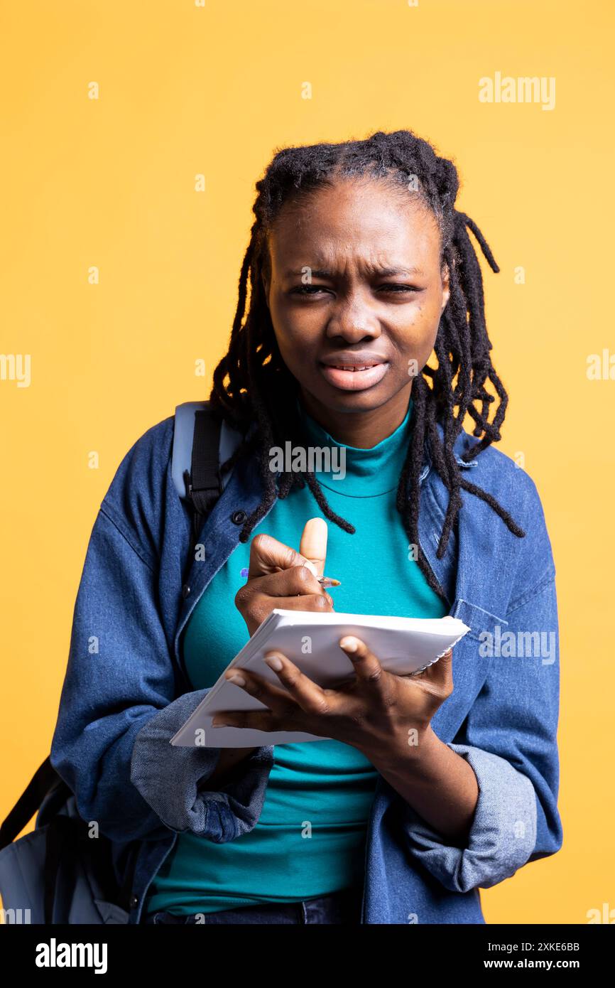 Girl squinting eyes, reading and writing for school exam on notepad ...