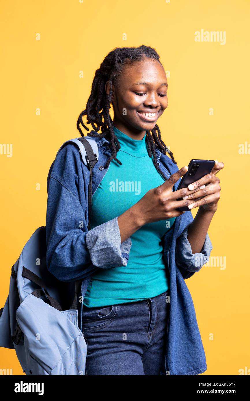 Radiant girl laughs while texting school colleague using cellphone ...