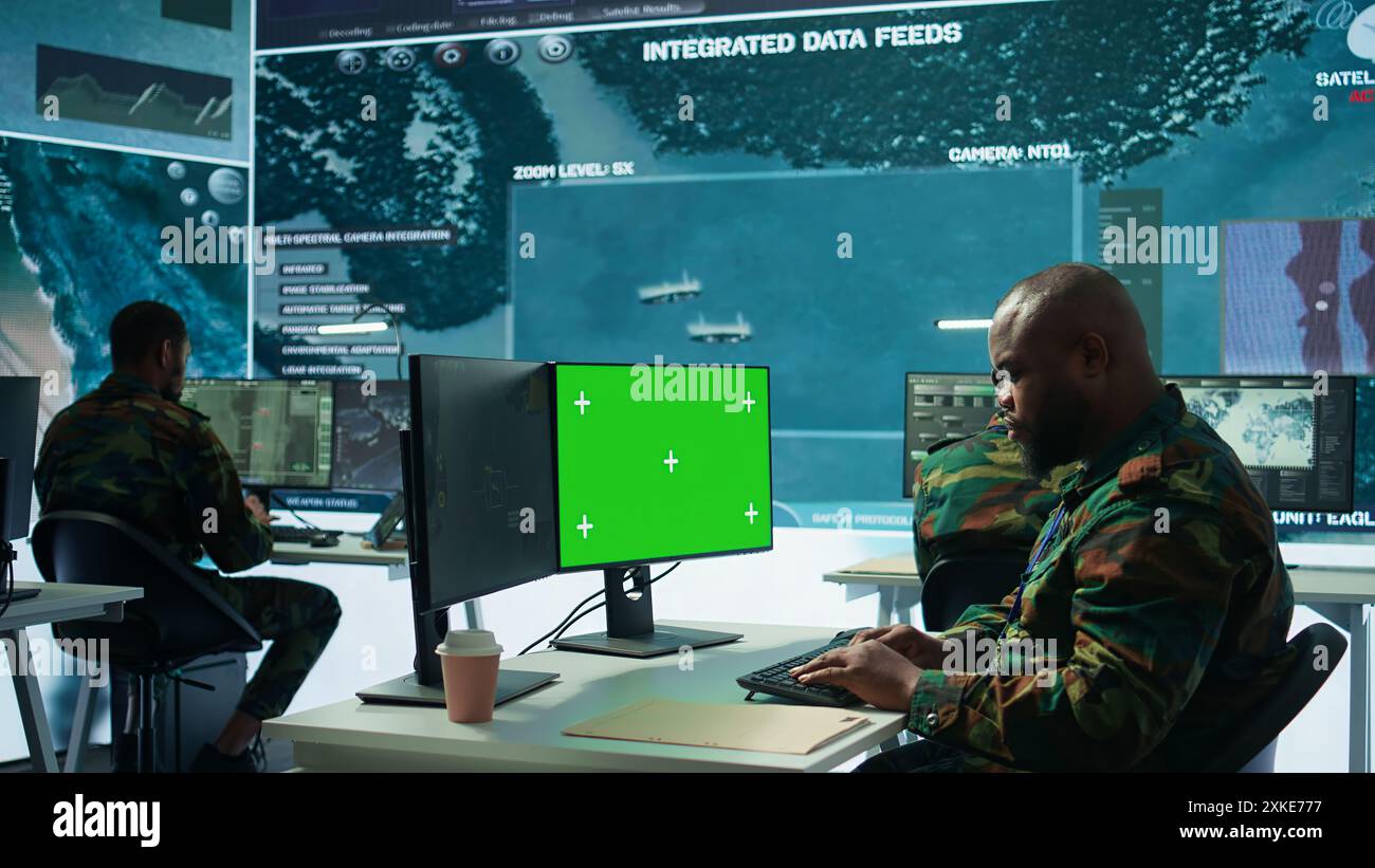 Military specialist monitors satellite data next to green screen ...