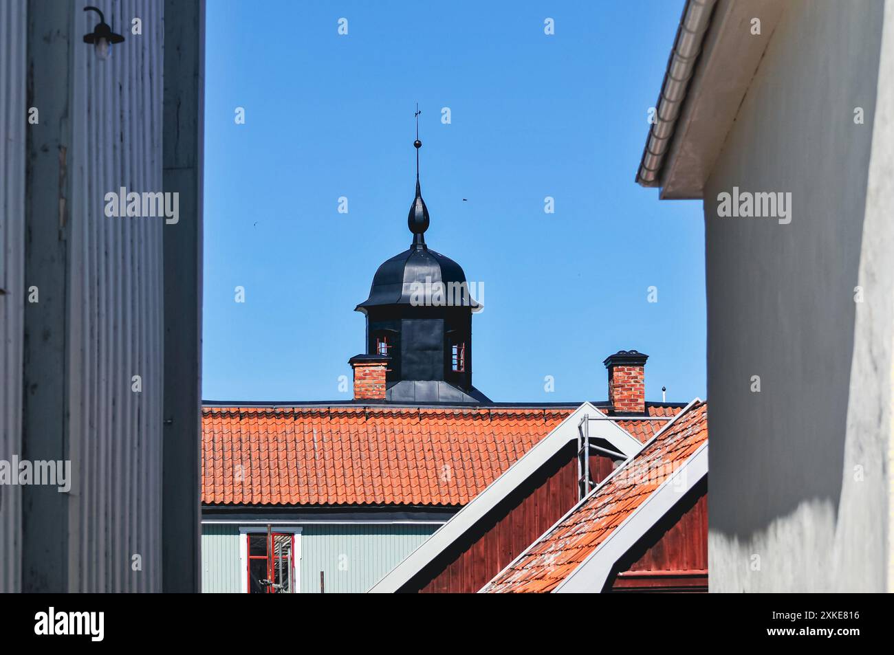 View of a church tower seen between buildings Stock Photo - Alamy