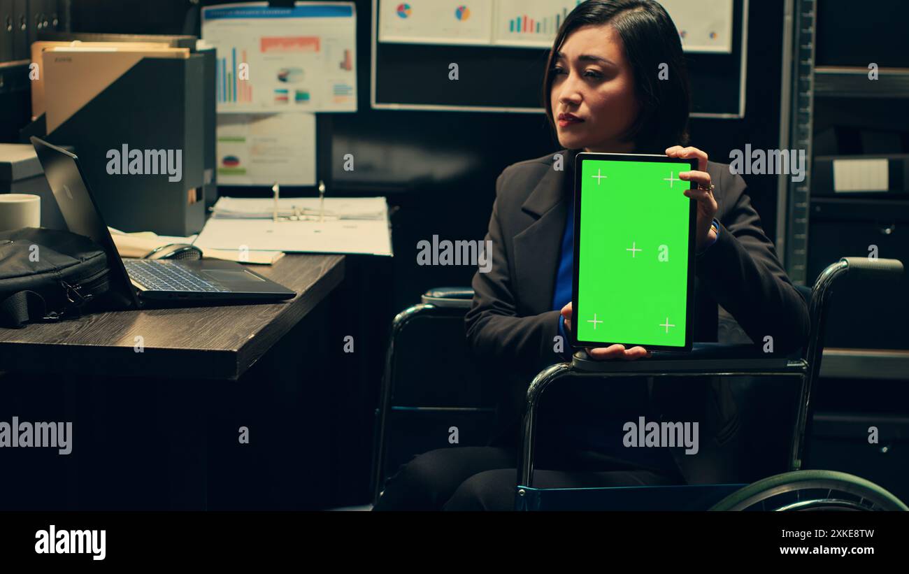 Detective wheelchair user holds greenscreen layout on tablet, using ...
