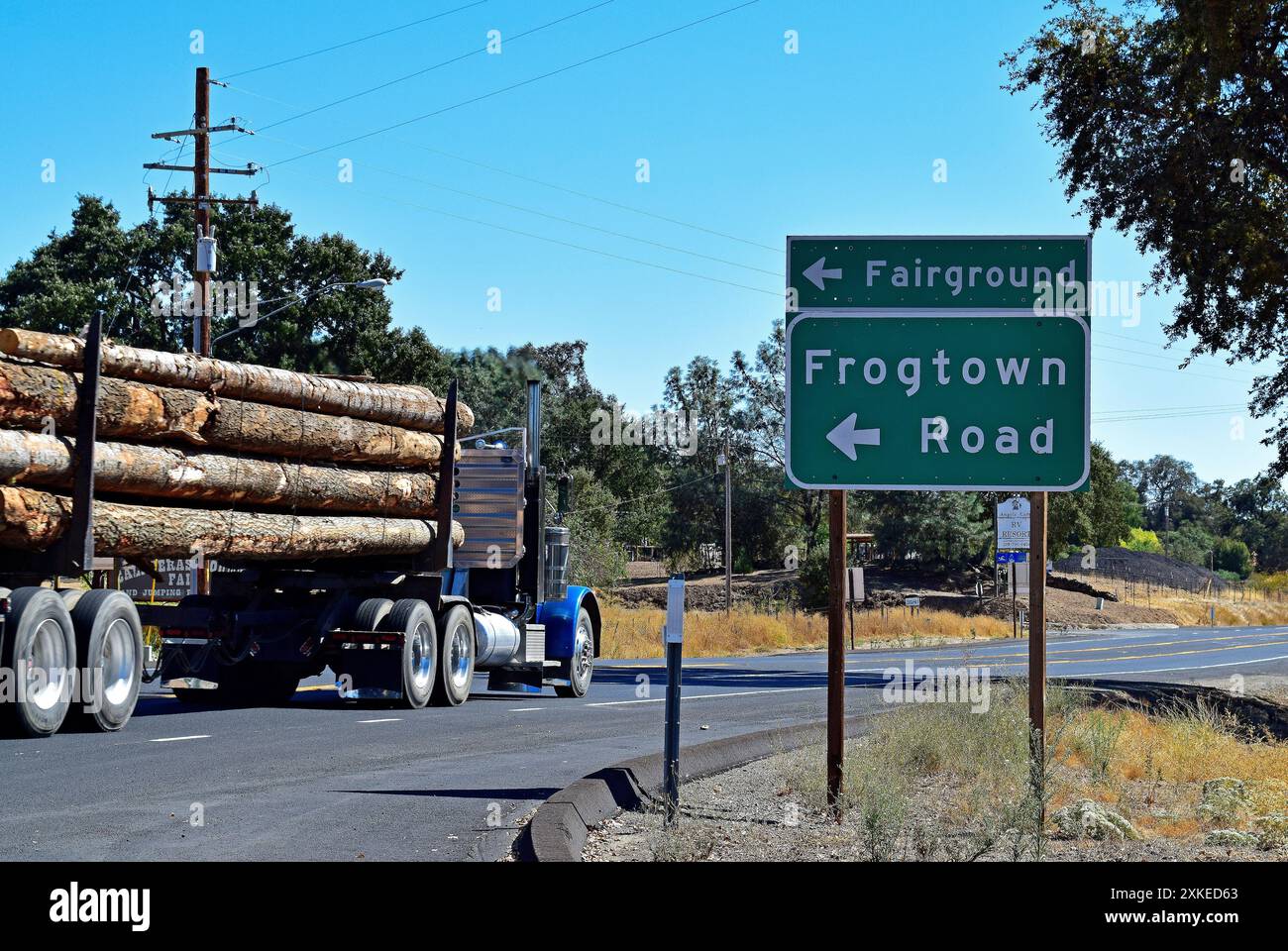 Lumber truck passes Frogtown road and Fairground direction sign in ...