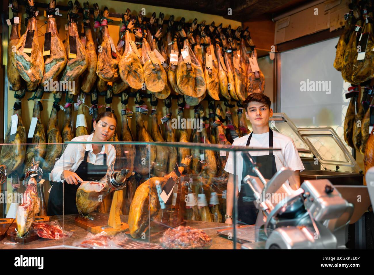 Young couple work together in butcher shop - they cut traditional ...
