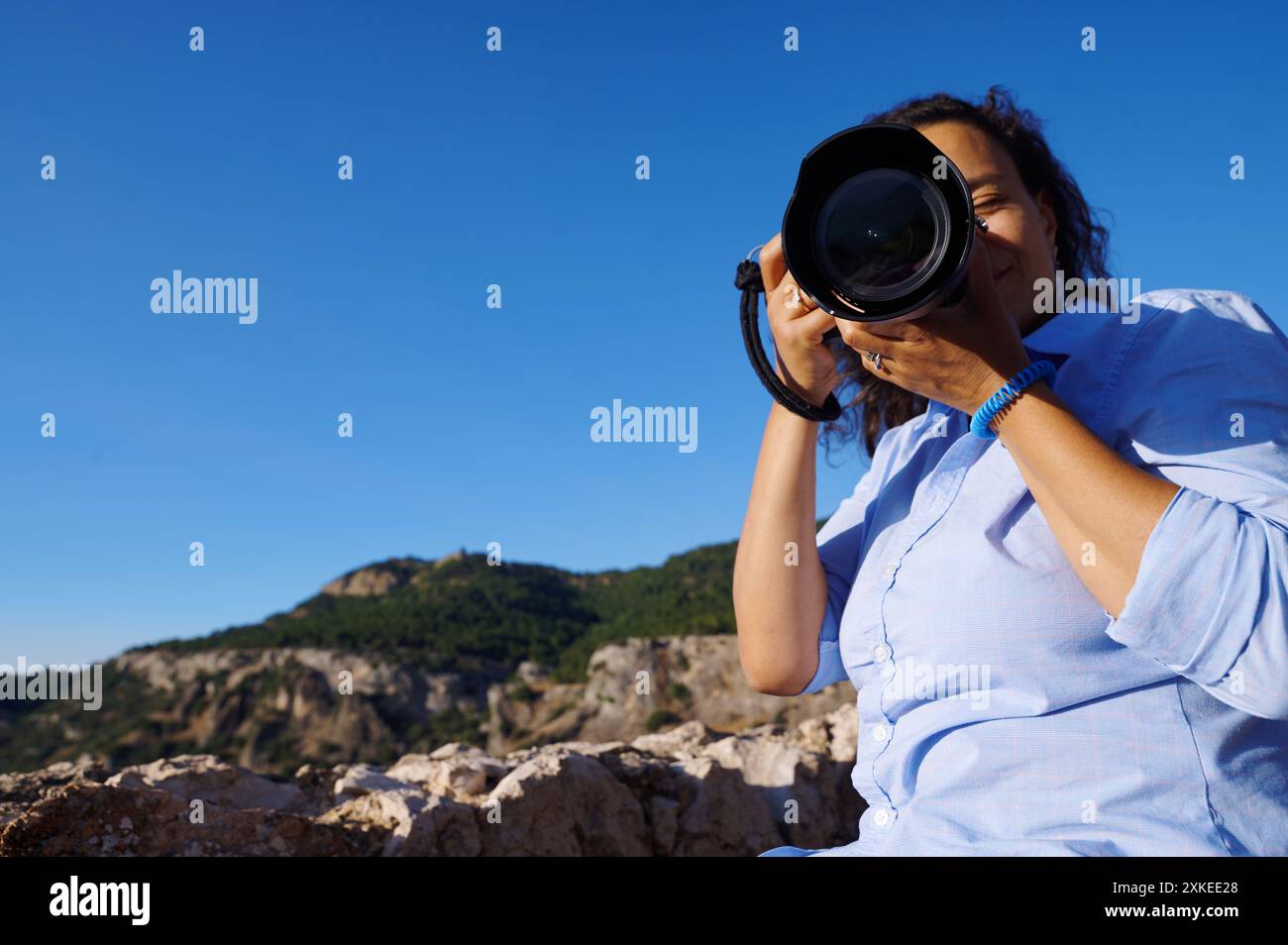 Female photographer capturing a beautiful mountain landscape with a ...