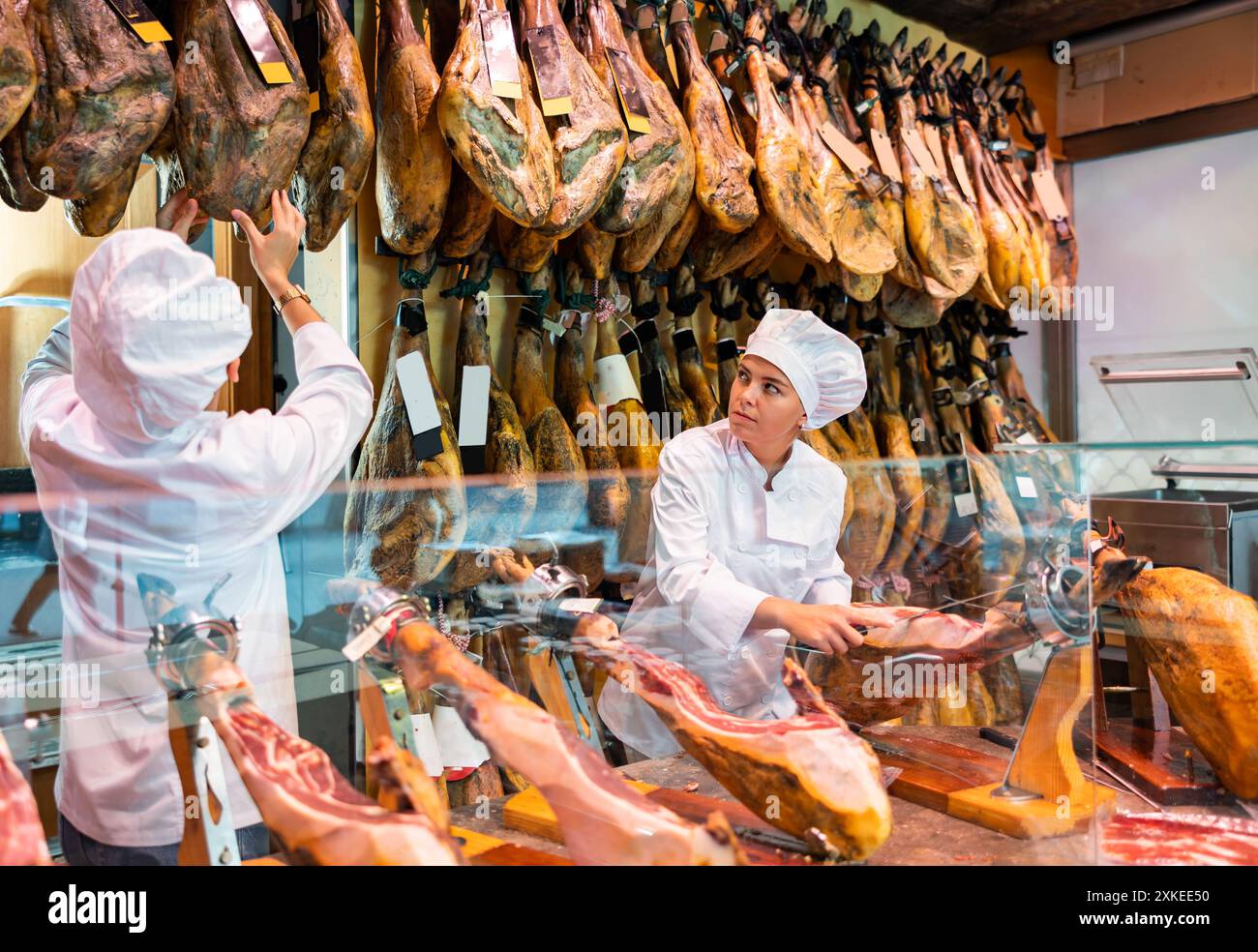 Young man and woman selling spanish jamon at counter Stock Photo - Alamy
