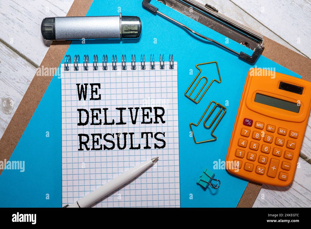 WE DELIVER RESULTS text on notebook with pen on a chart background ...