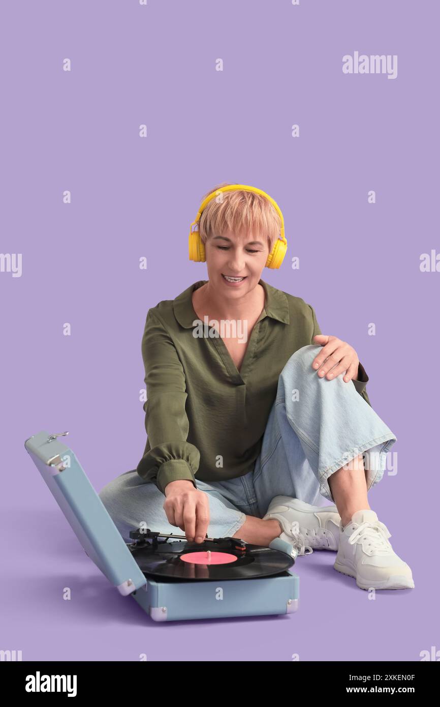 Mature woman in headphones with record player listening to music on ...