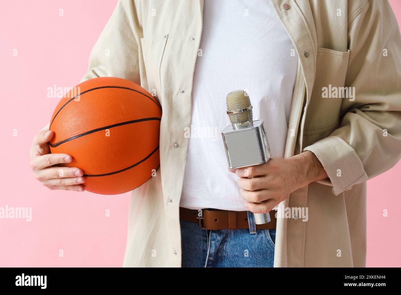 Male reporter with microphone and ball on pink background, closeup ...