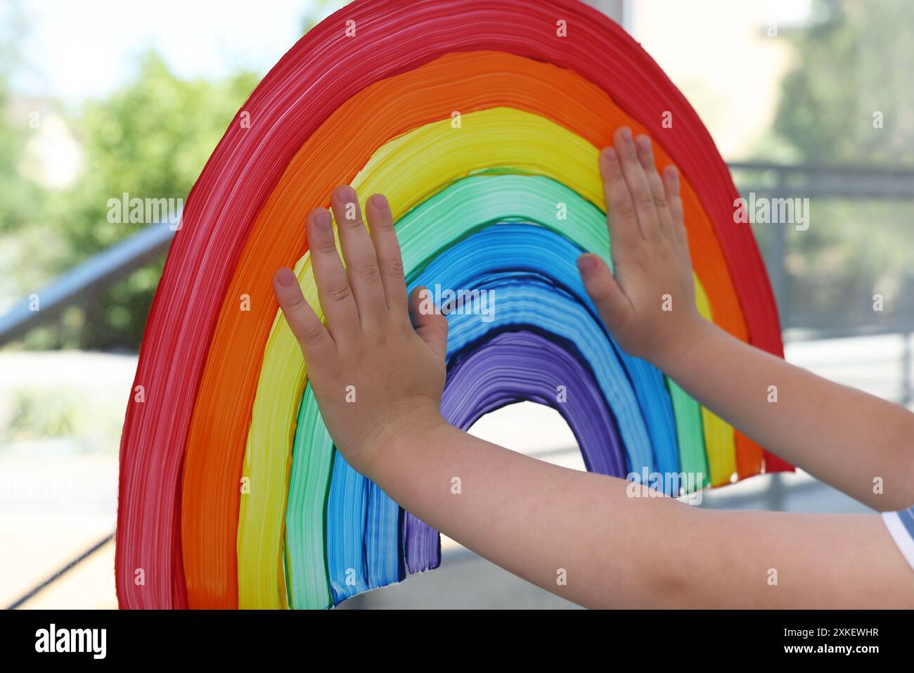 Little boy touching picture of rainbow on window, closeup Stock Photo ...
