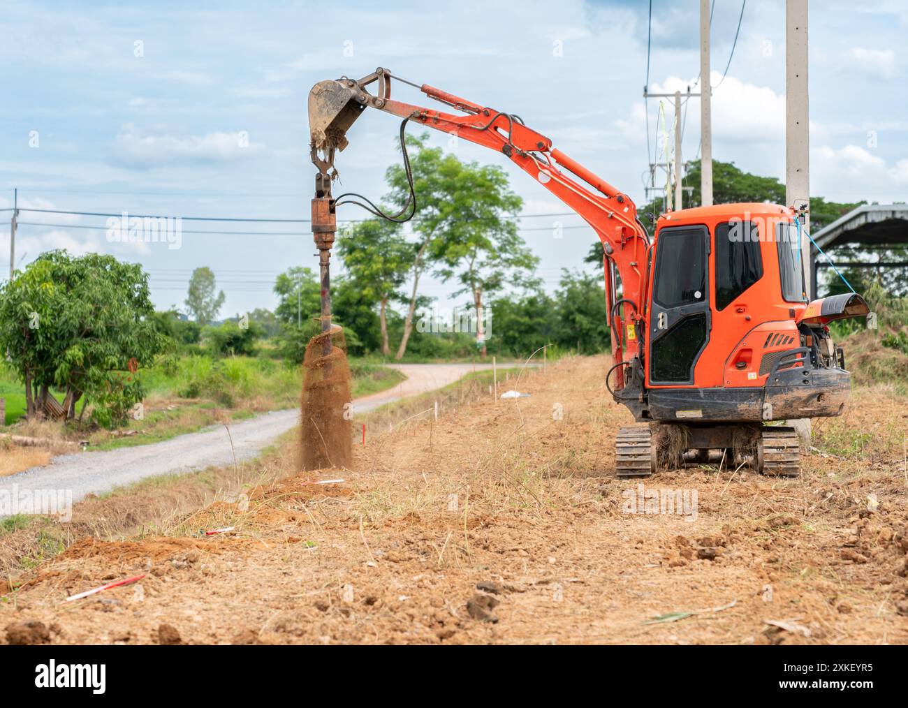 Mini excavator makes holes with auger drill for install pole fence in ...