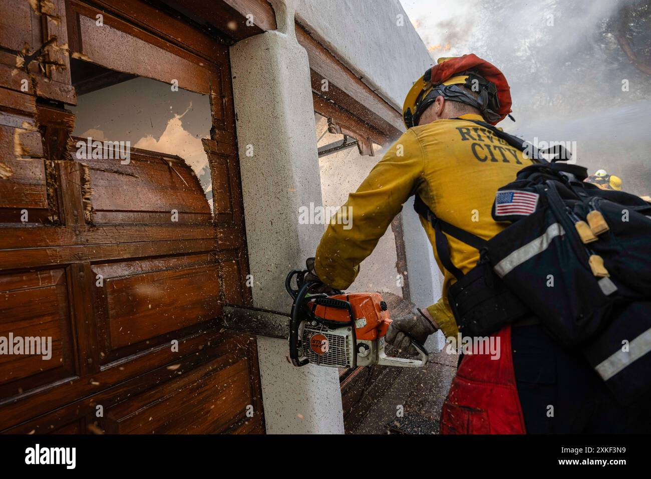 A Cal Fire Firefighter cuts through a burning garage with a Chainsaw ...