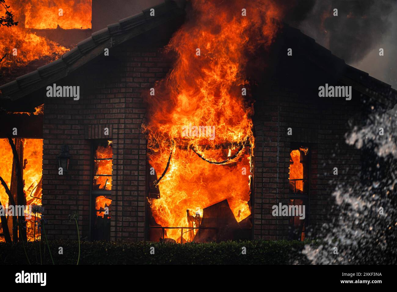 Flames flow from a living room window of a Riverside home as it burns ...