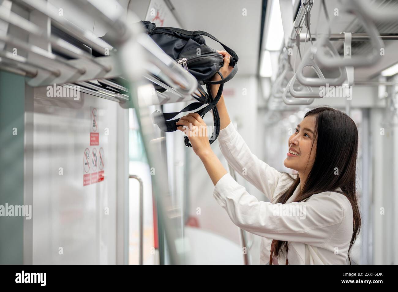 A happy, charming young Asian female commuter is putting her backpack ...