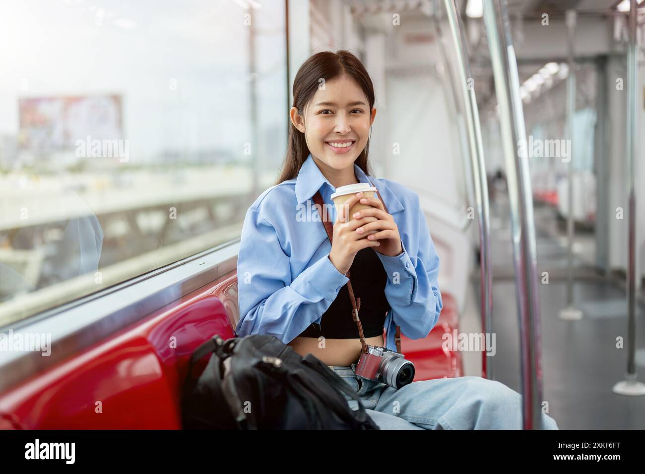 A beautiful, happy young Asian female passenger is sipping coffee while ...