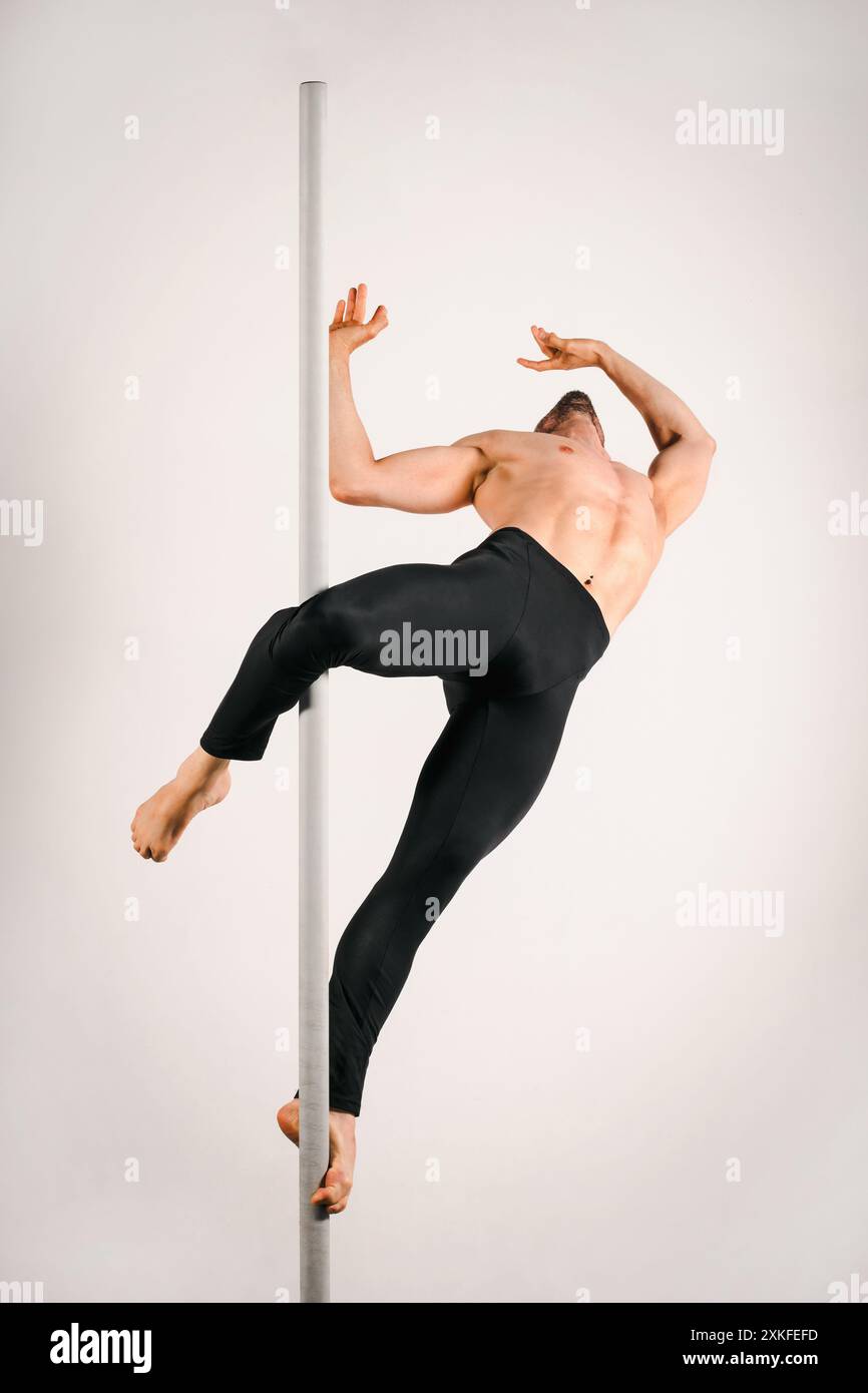Muscular male pole dancer is gracefully holding the cupid pose ...