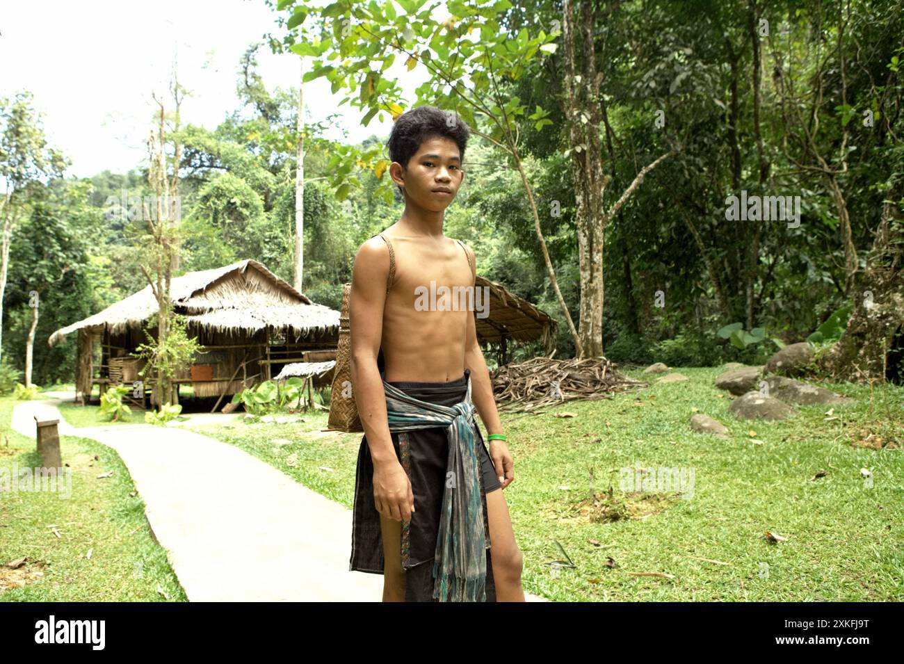 A tourism worker wearing indigenous attire walks on a concrete walkway ...