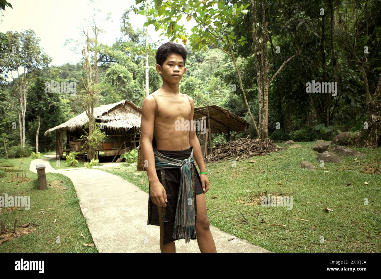 A tourism worker wearing indigenous attire walks on a concrete walkway ...