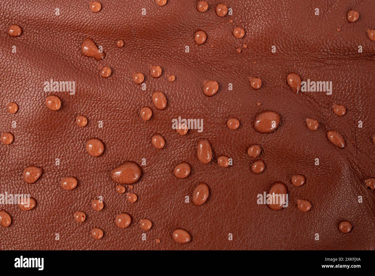 Round water drops on red brown leather texture, top view, soft focus ...