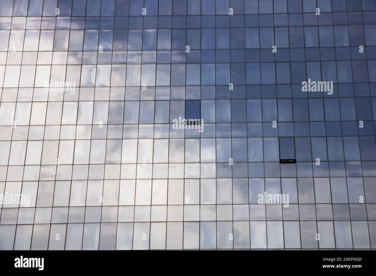 A building reflects a blue sky in its windows, featuring a rectangular ...