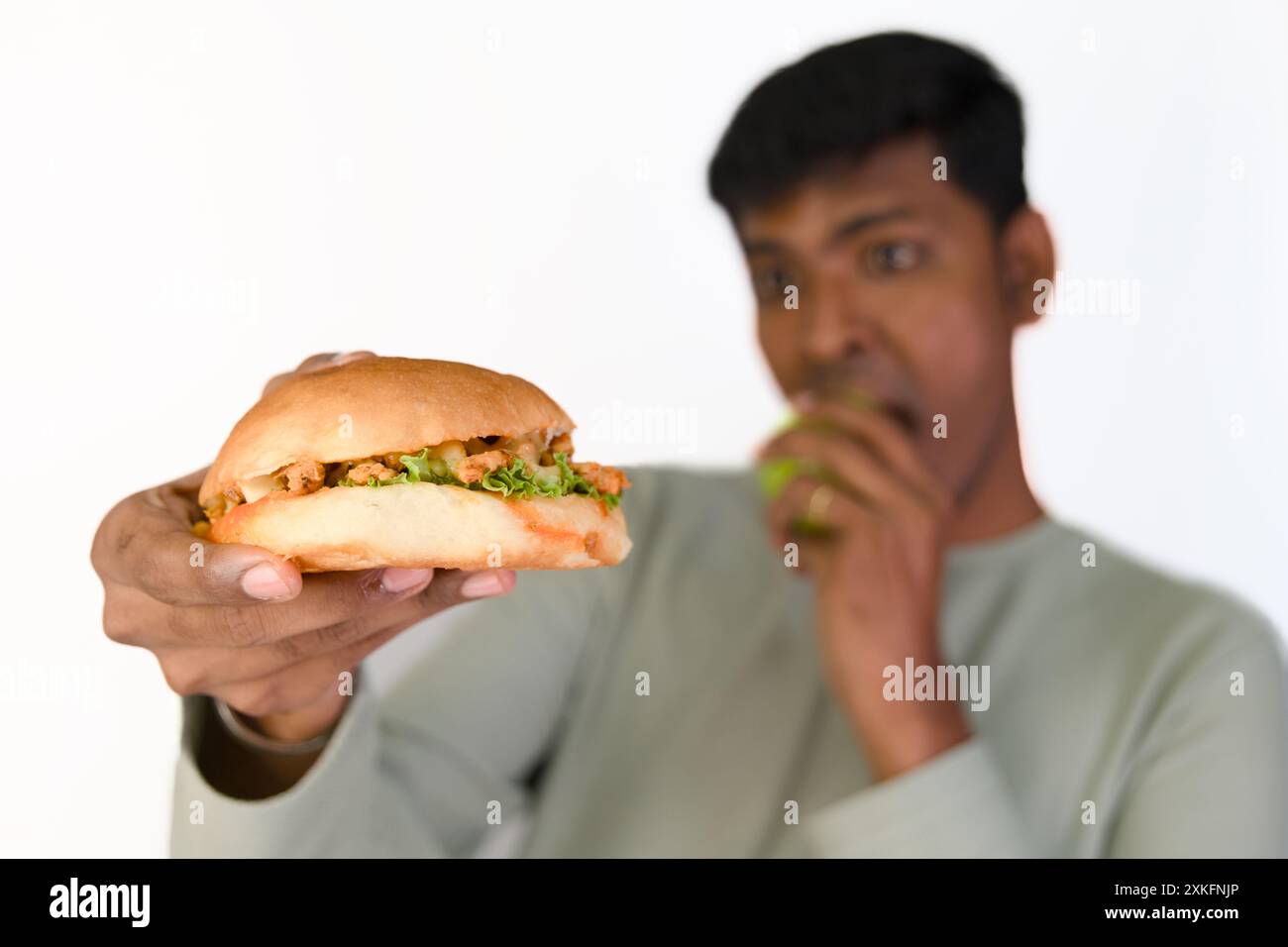 A man can't decide which to devour first, holding out a juicy burger ...