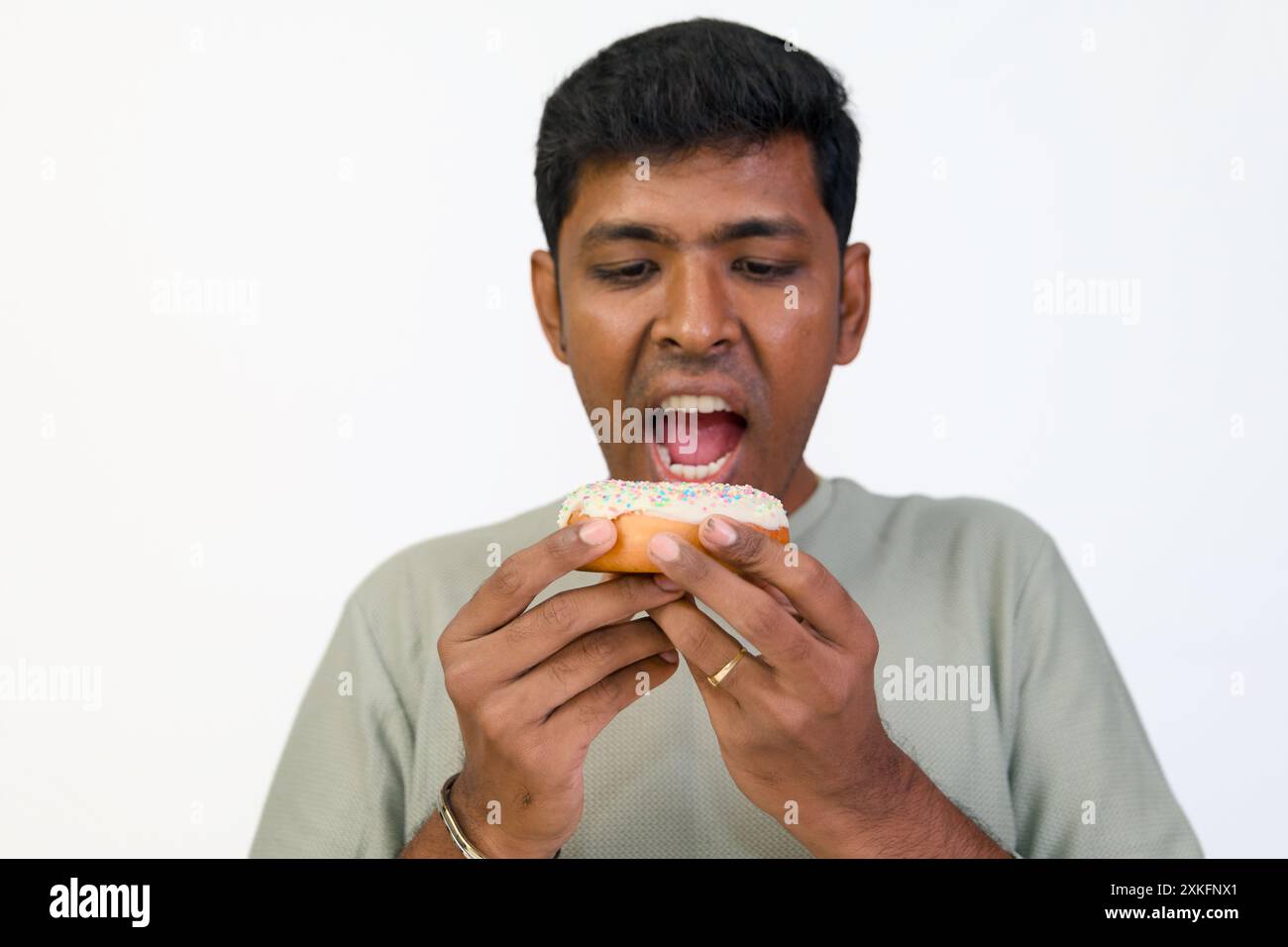 Man about to take a big bite of a delicious frosted donut with ...