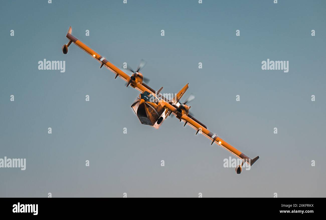 A firefighting aircraft is in action above a clear sky, engaged in ...