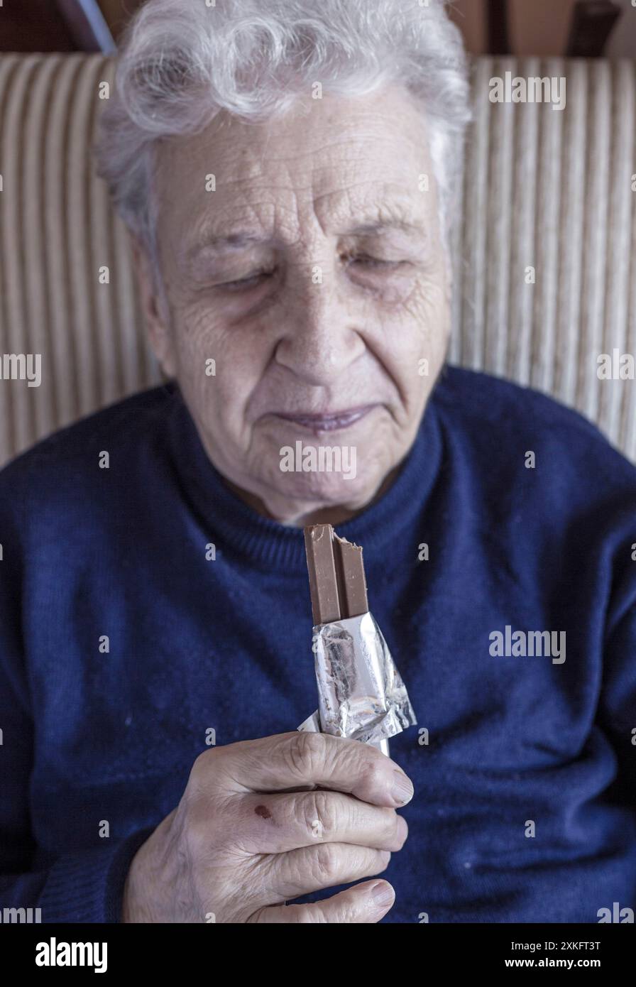 A lovely senior woman eating a chocolate bar Stock Photo - Alamy