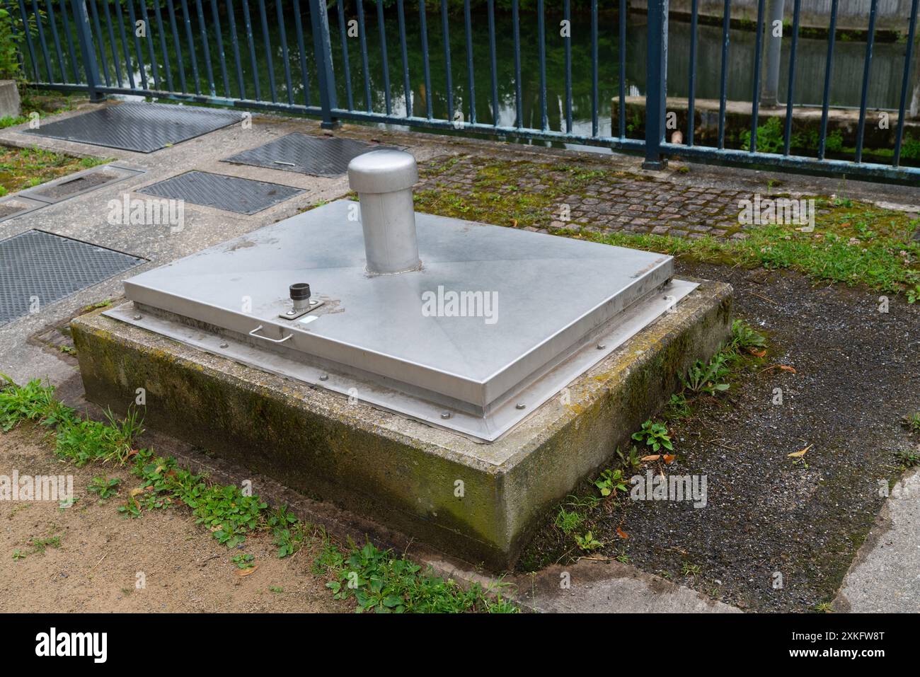 Aluminum water chamber on the ground of an urban park, with metal pipes ...