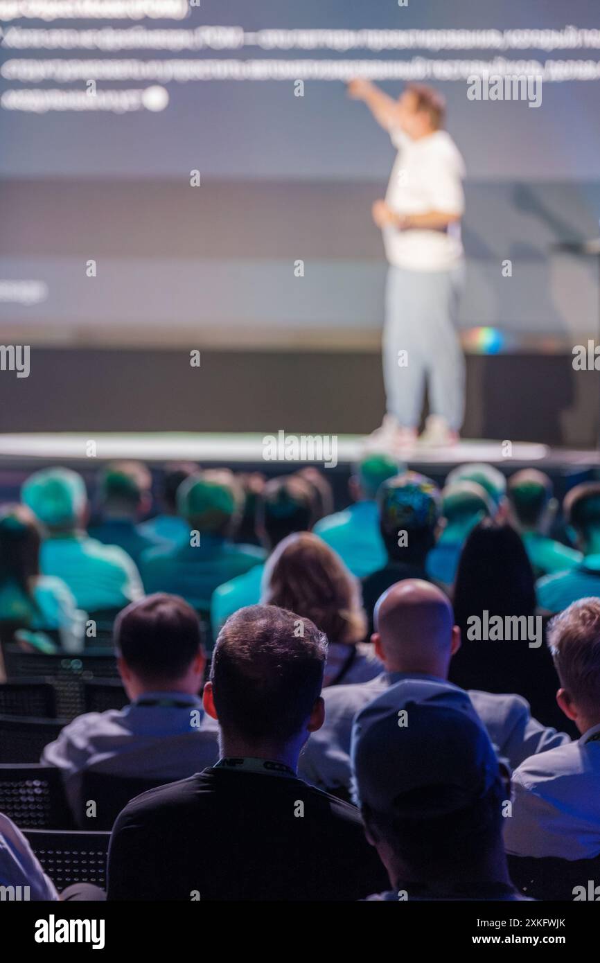 Speaker delivering a presentation at a conference with a large ...