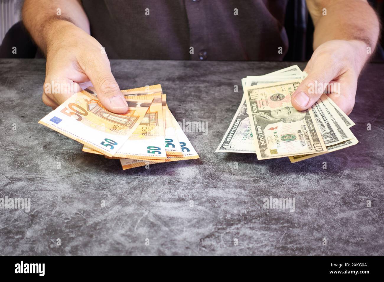 Man showing a wad of dollar bills in one hand and euros in the other ...