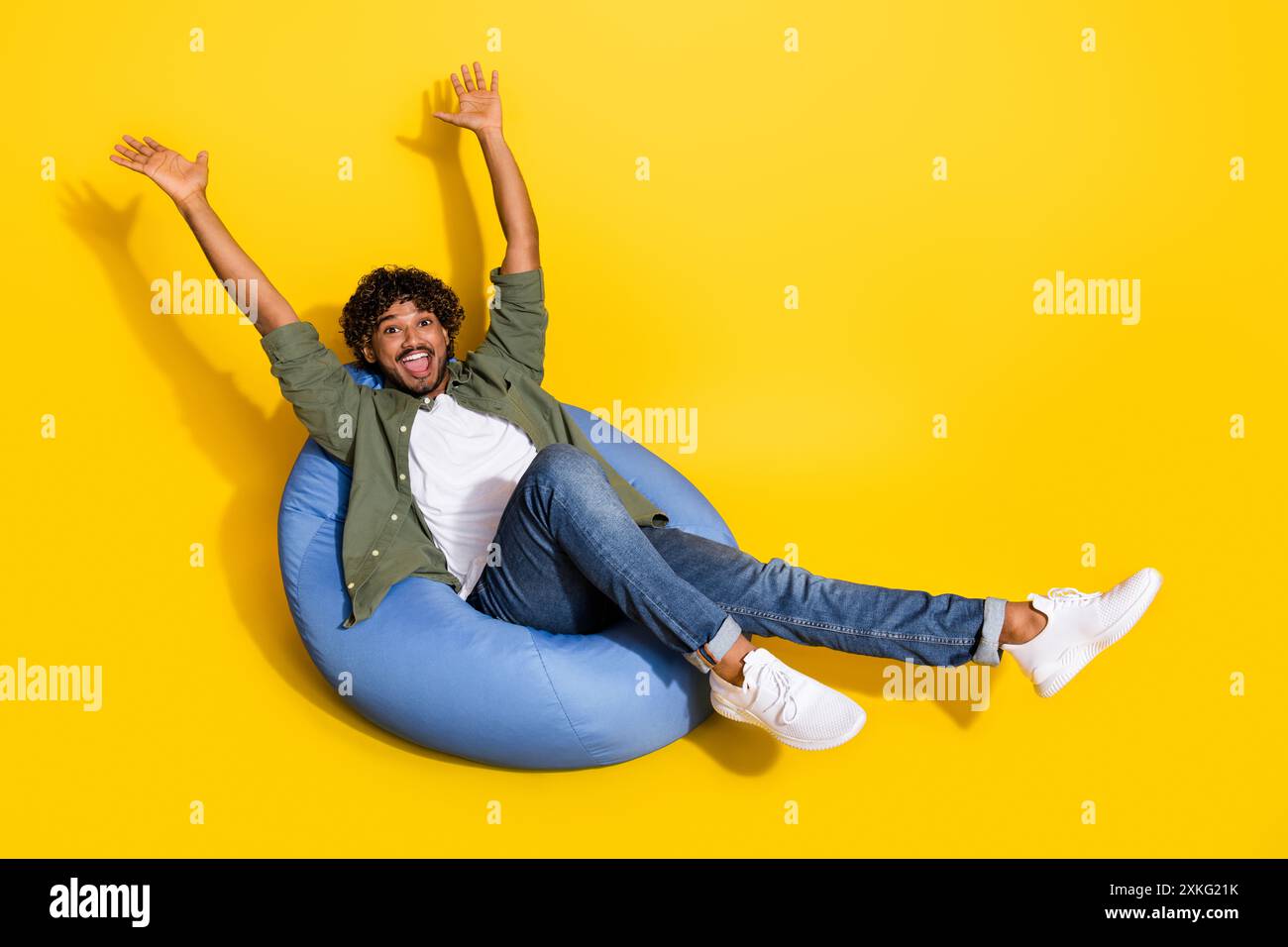Photo of young funny mexican guy in khaki shirt and jeans raised hands ...