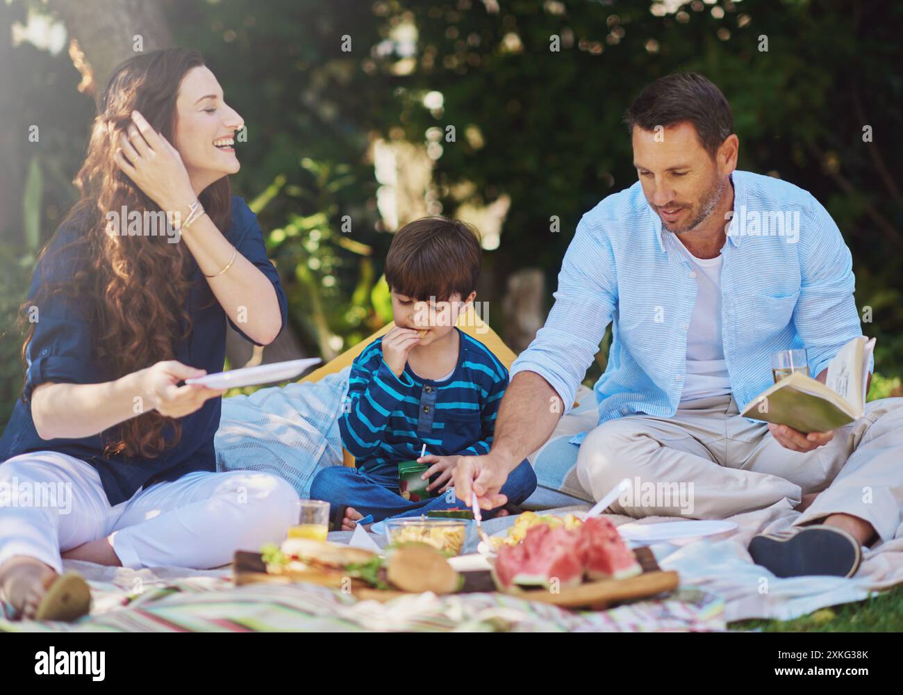 Happy family, picnic and eating lunch at park, laughing and bonding ...