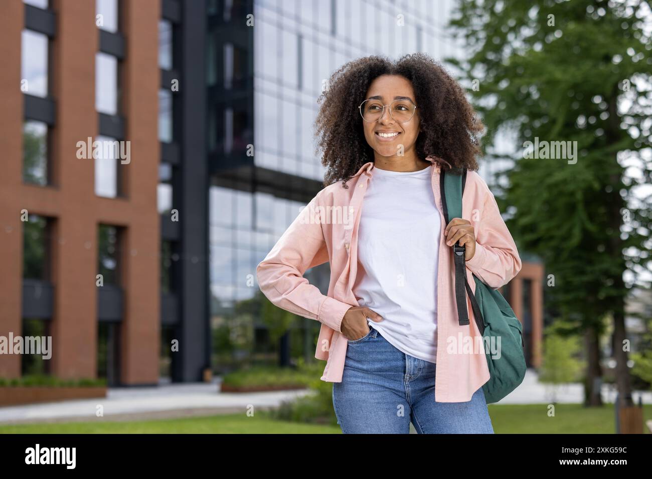 Confident young student with backpack standing in front of modern ...