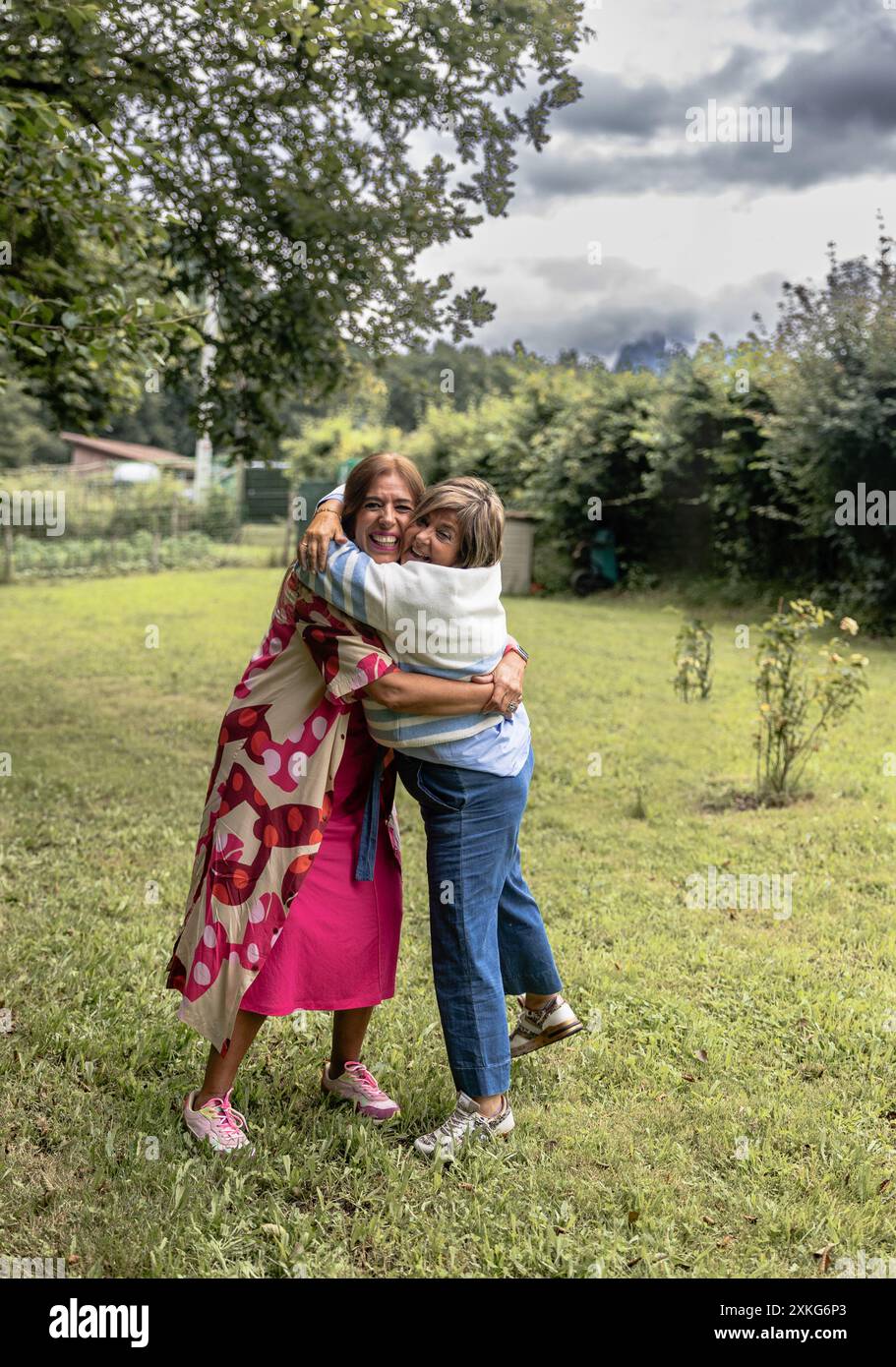 Two friends embrace warmly in a green countryside setting, celebrating ...