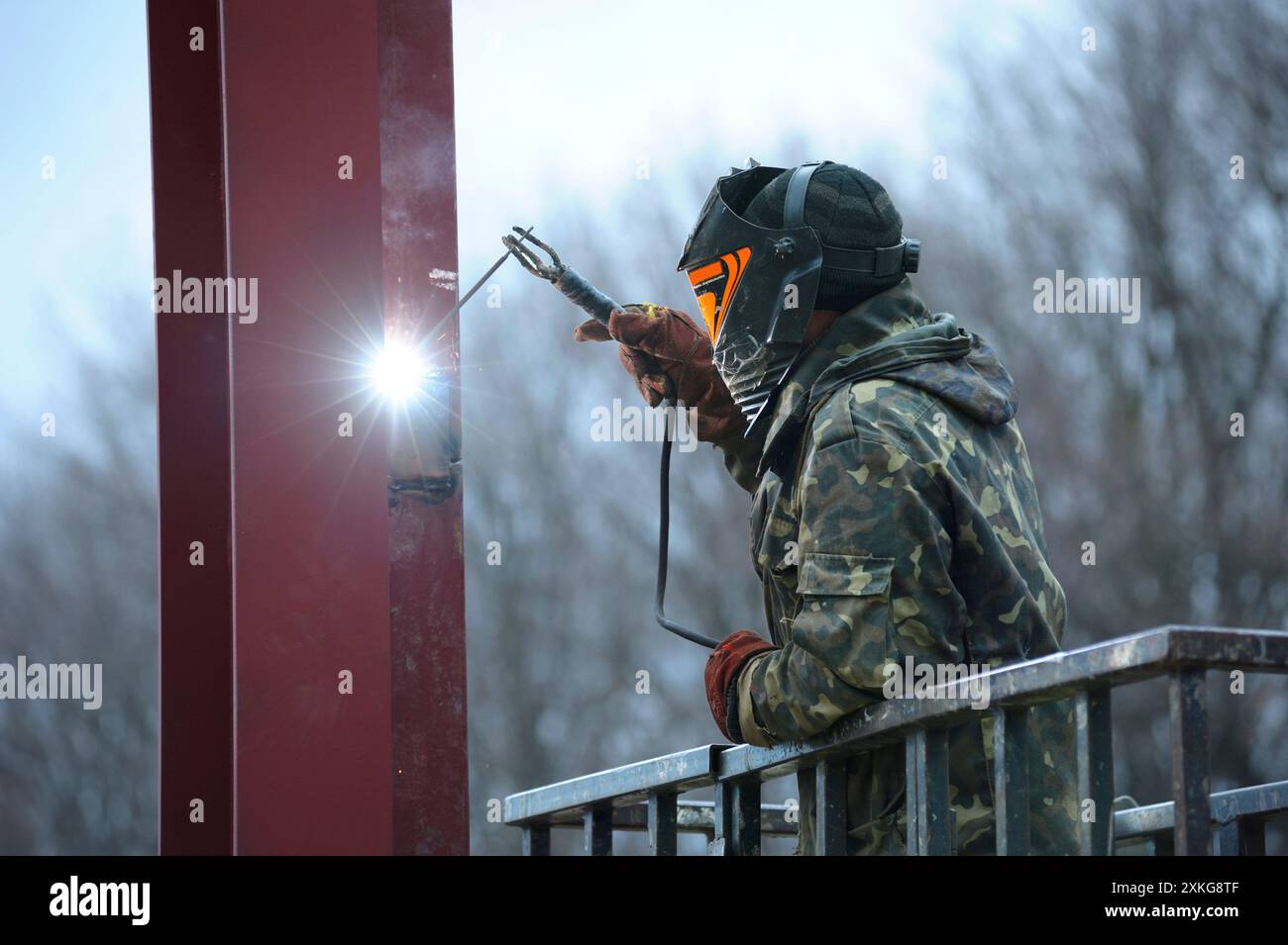 Worker welding metal carcass using truck mounted lift, construction ...