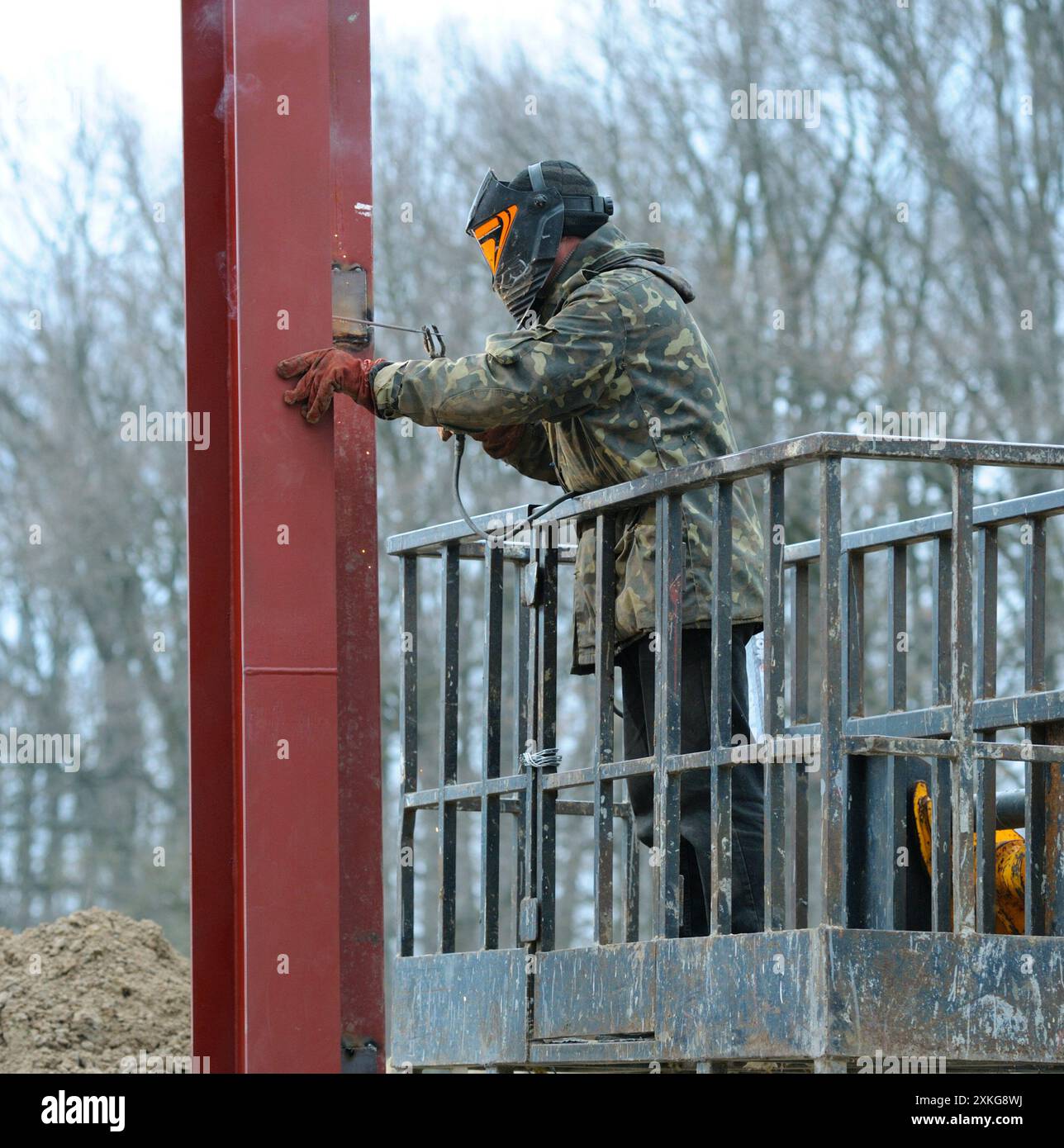 Worker welding metal carcass using truck mounted lift, construction ...