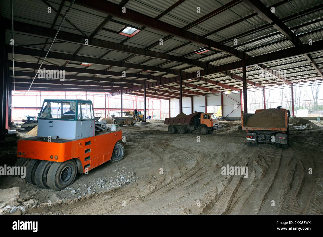 Construction site of a hangar building, an excavator and dump trucks ...