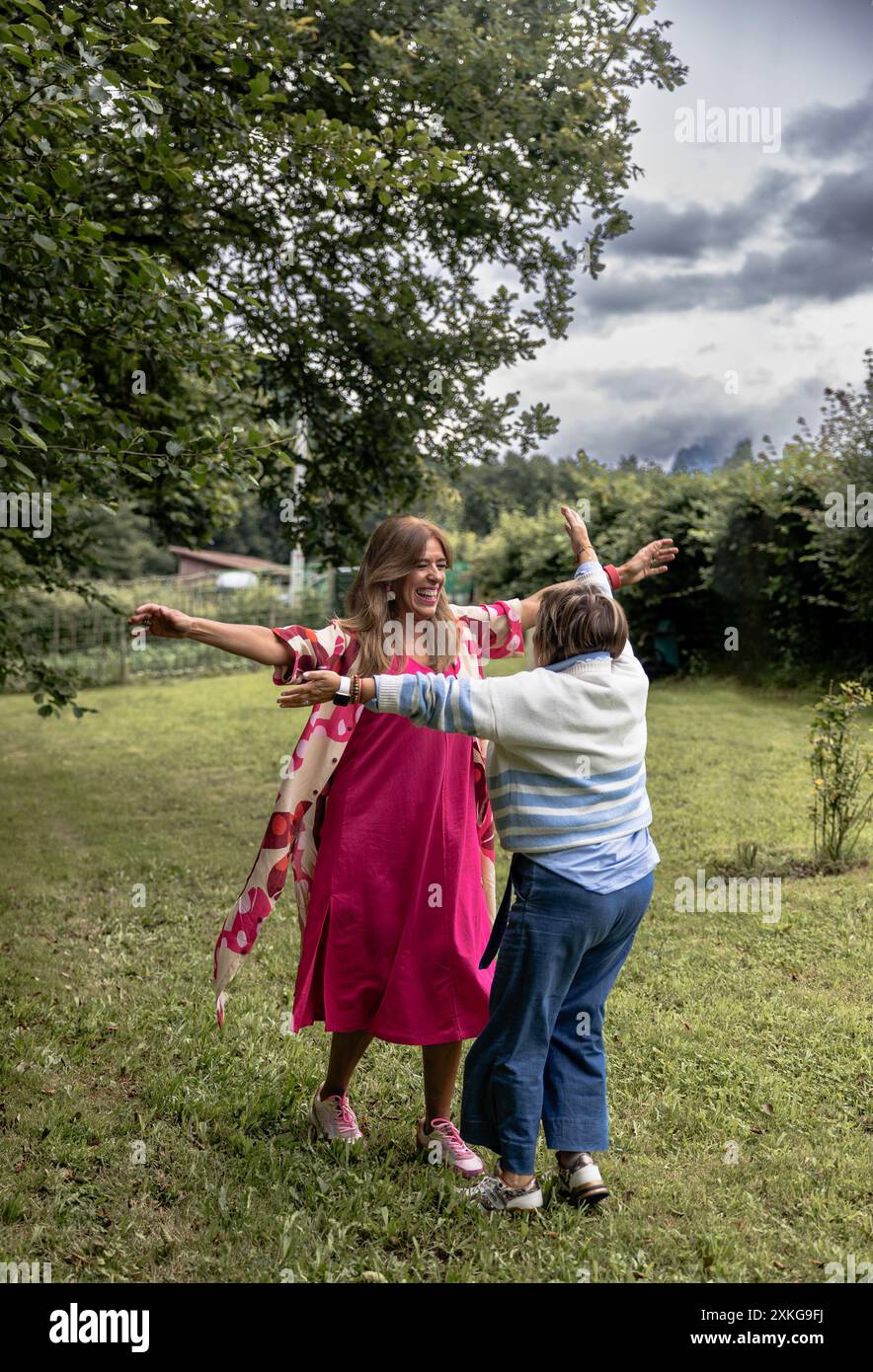 Two women friends embrace joyfully in a lush countryside setting as ...