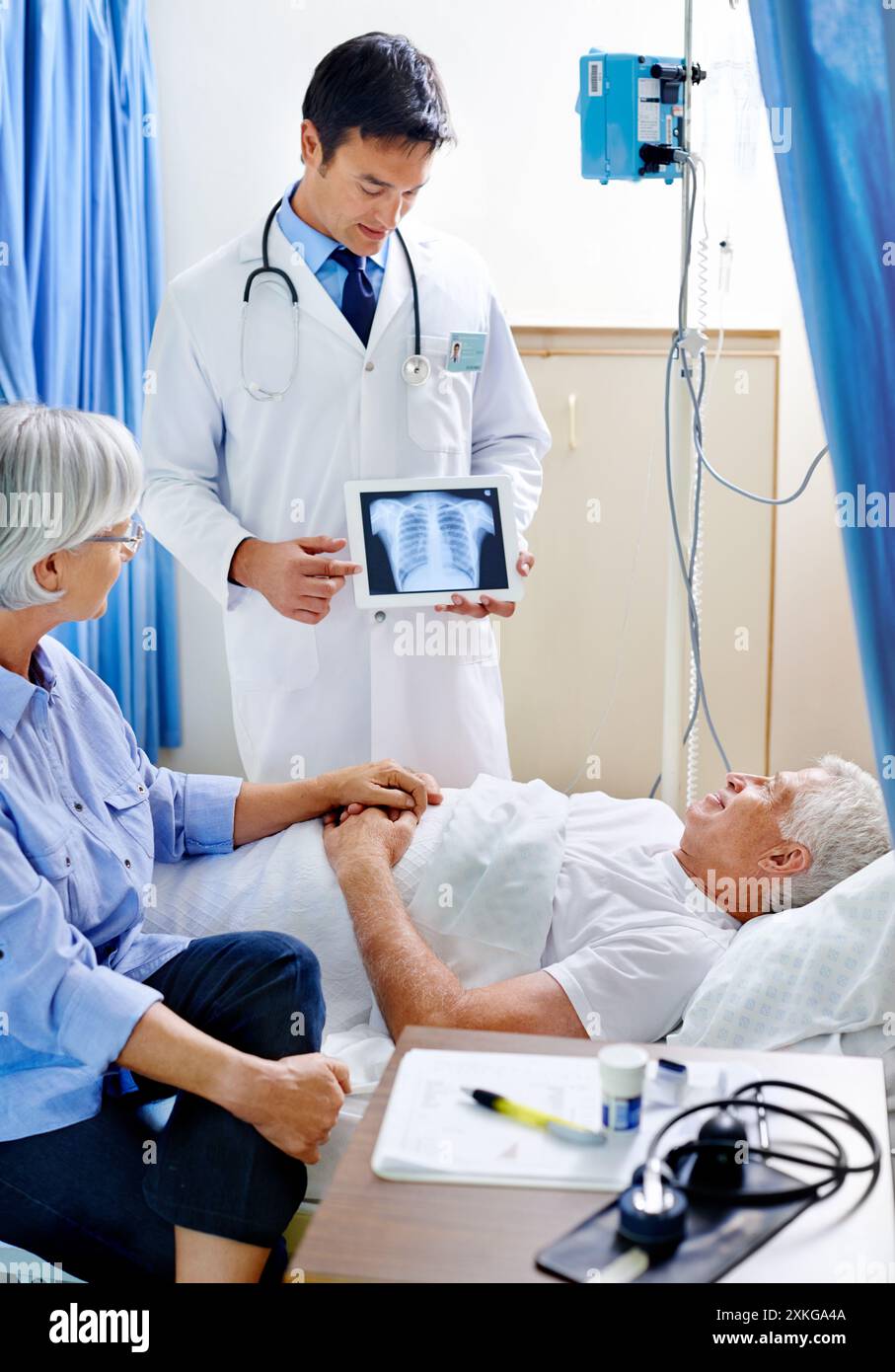Doctor, senior and patient in bed for consultation with xray on screen ...