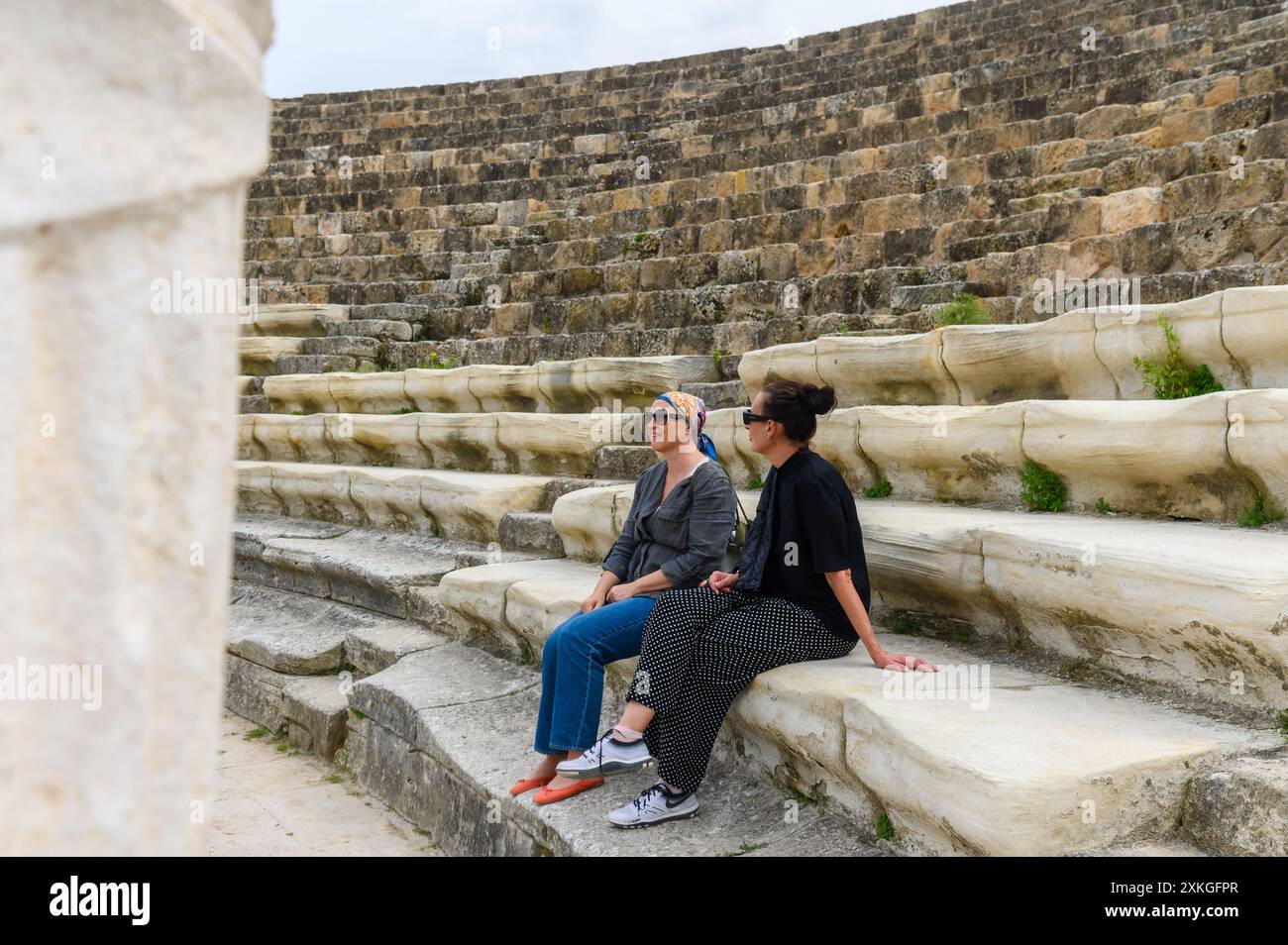 2 women sitting in an amphitheater in an ancient ruined city ...