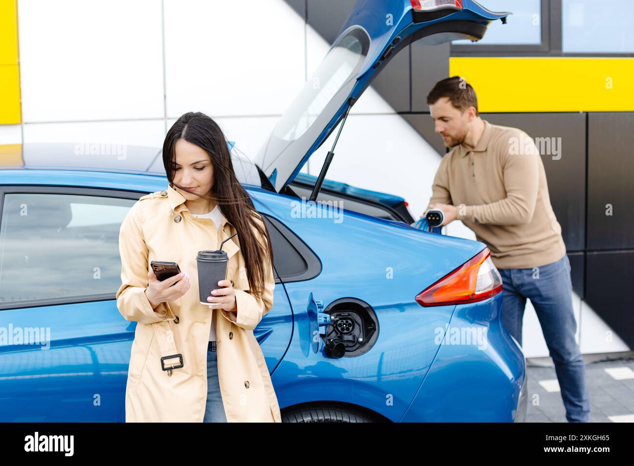 Young couple man and woman traveling by electric car having stop at ...