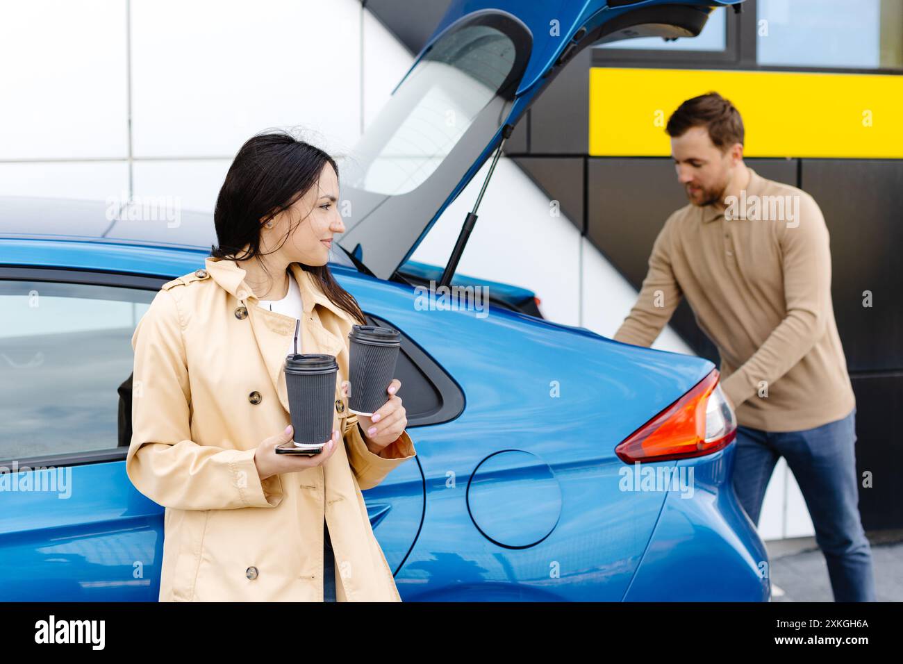 Young couple man and woman traveling by electric car having stop at ...