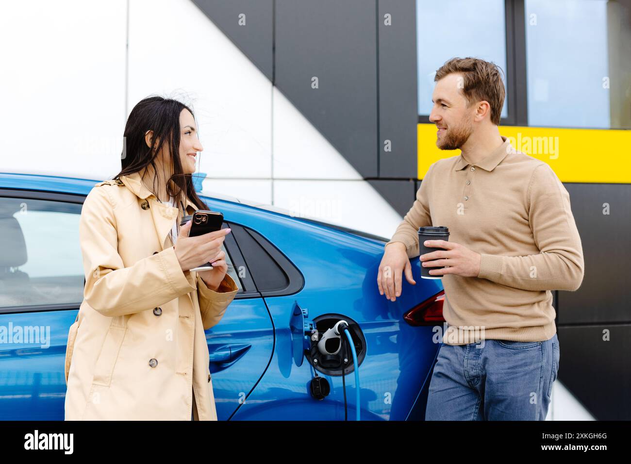 Young couple man and woman traveling by electric car having stop at ...