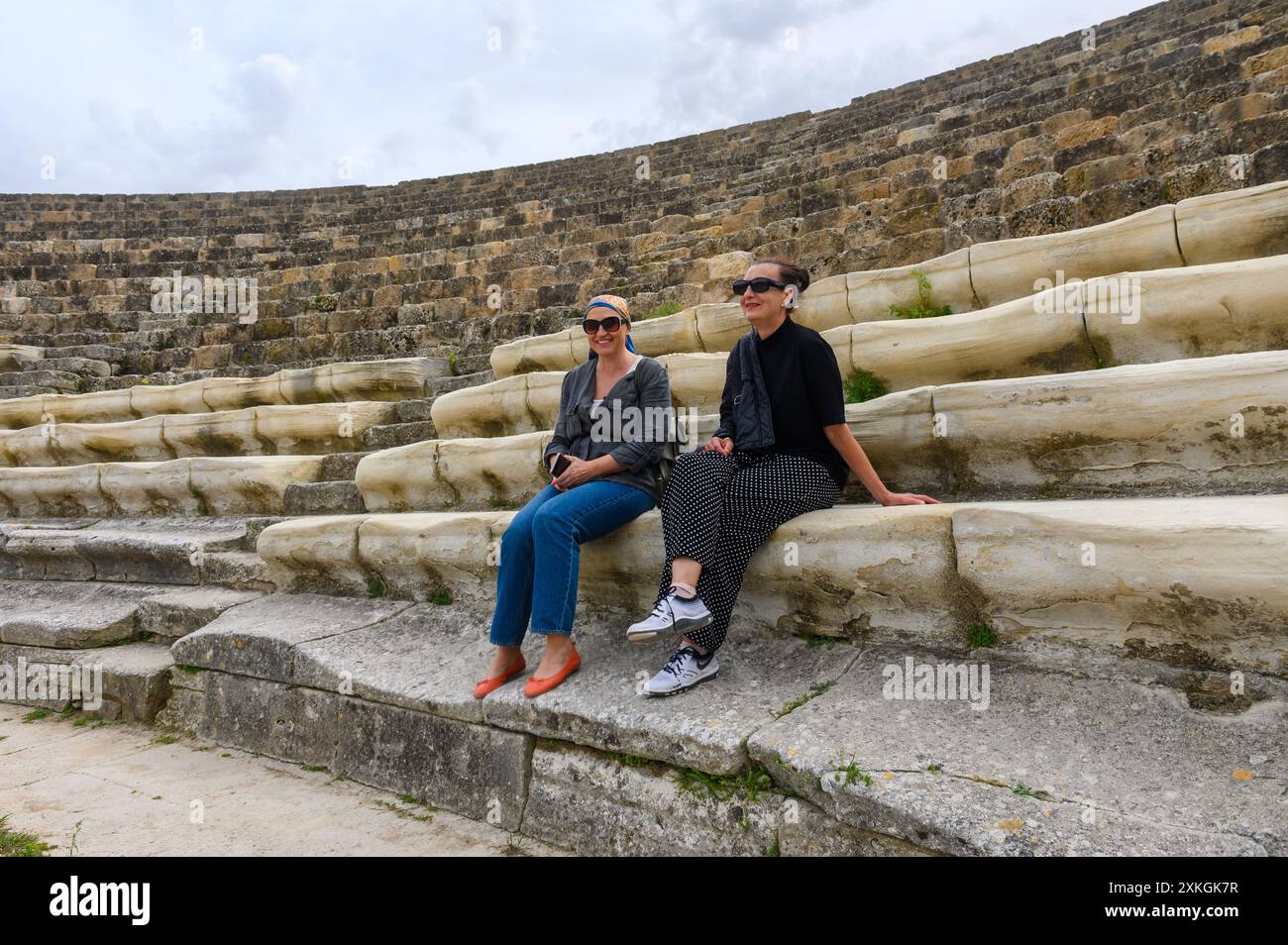 2 women sitting in an amphitheater in an ancient ruined city ...