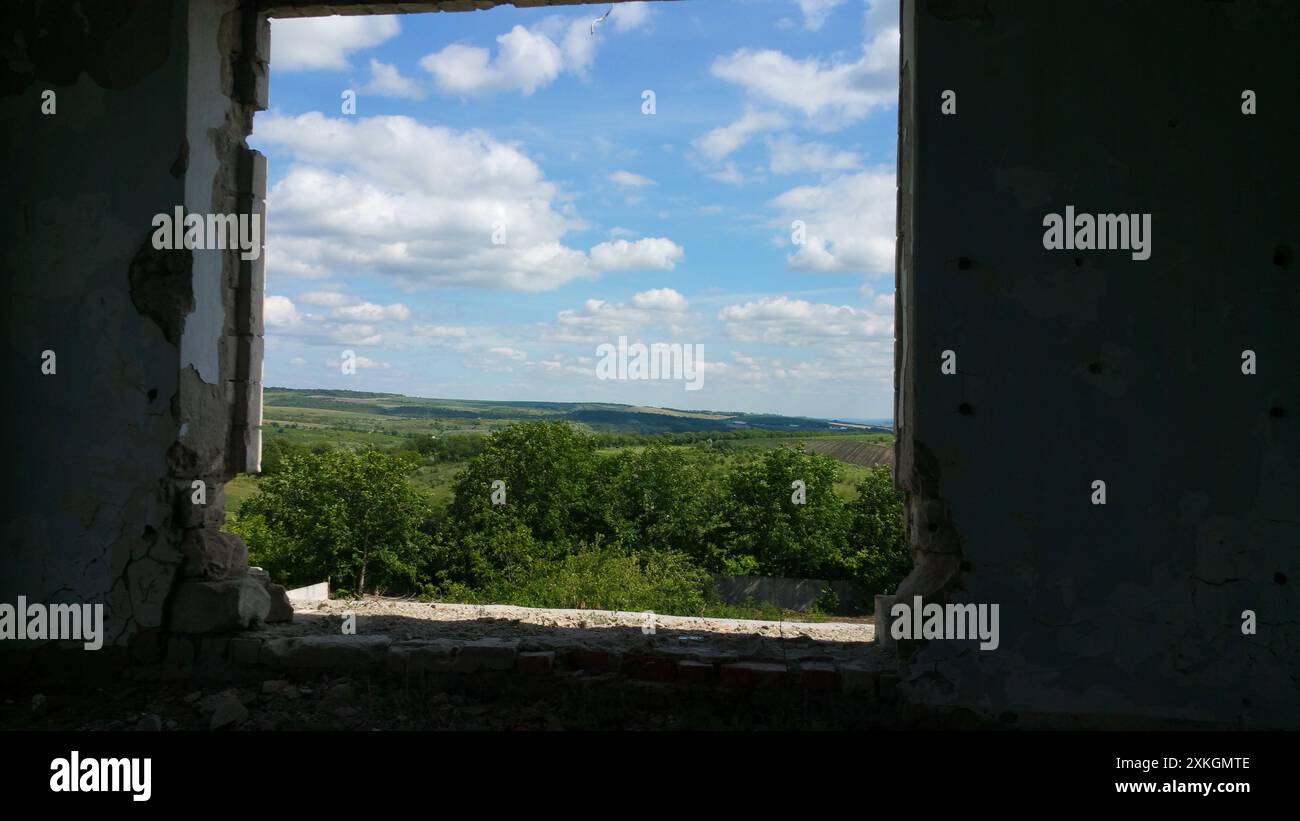 view from the old window of green meadows and blue sky with white ...