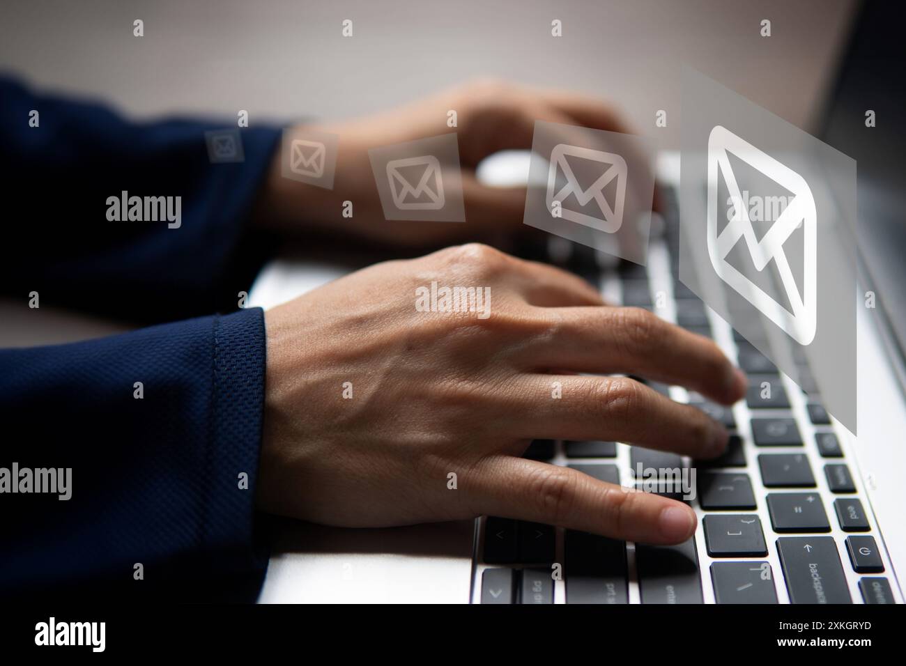 Close-up of a hands typing on a laptop keyboard with a several floating email icons. Sending and ...