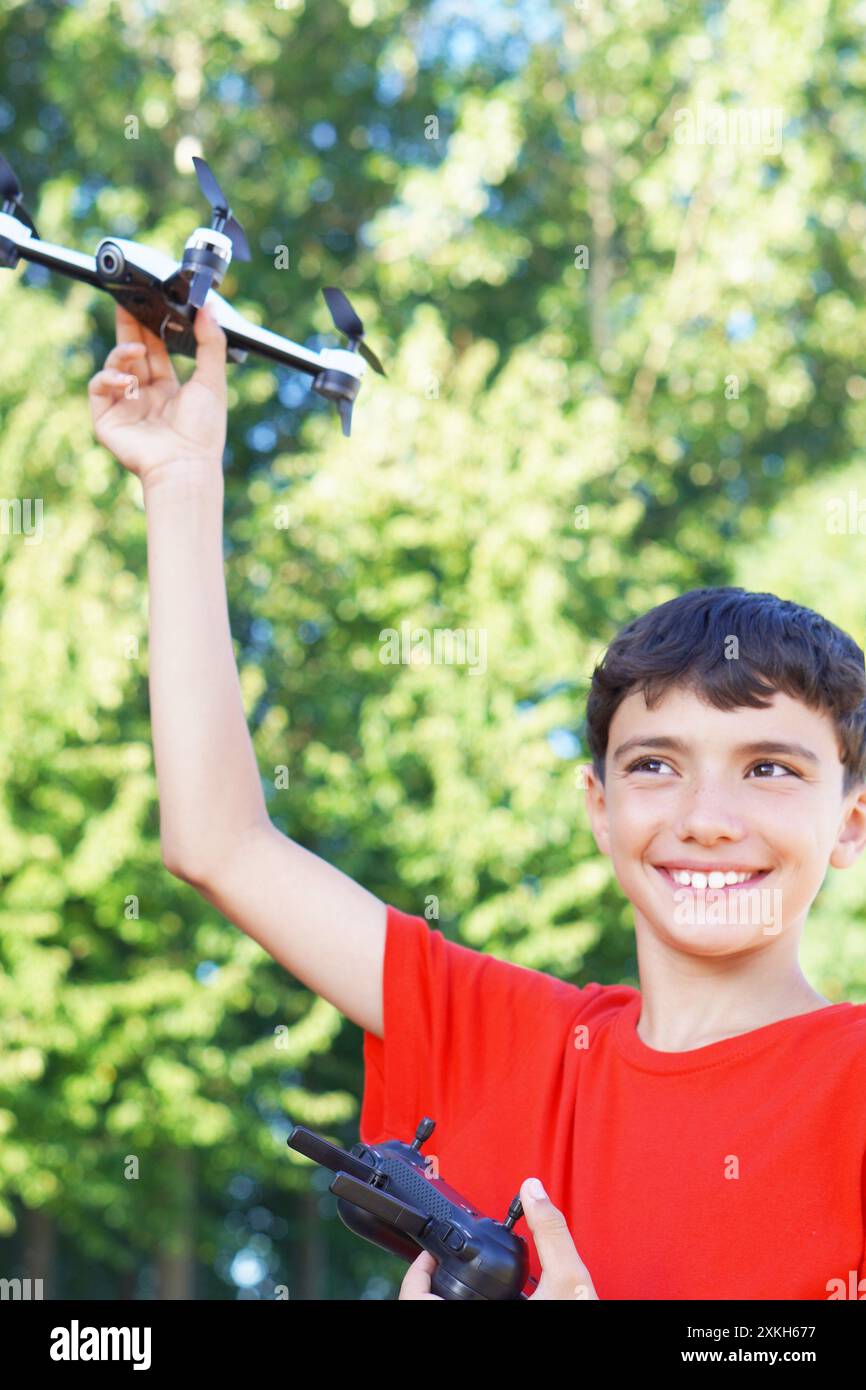 smiling tween boy playing, ready to fly drone in the field in ...