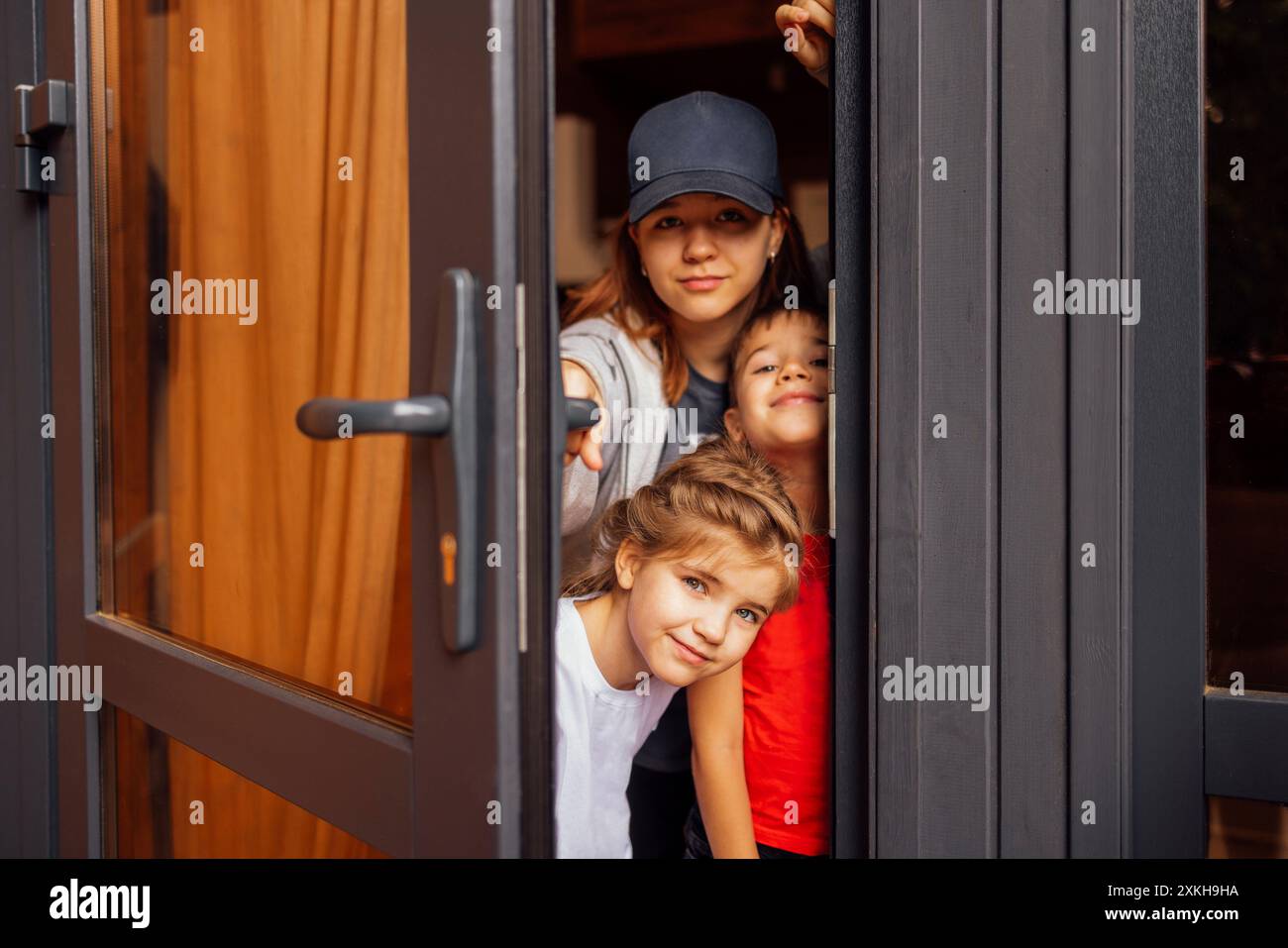 Cute children peek out of the doorway. A female teenager with her ...