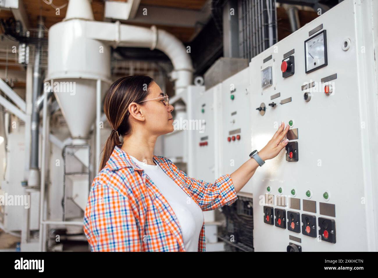 A young woman works at an elevator. An attractive female agronomist adjusts the machinery. The ...
