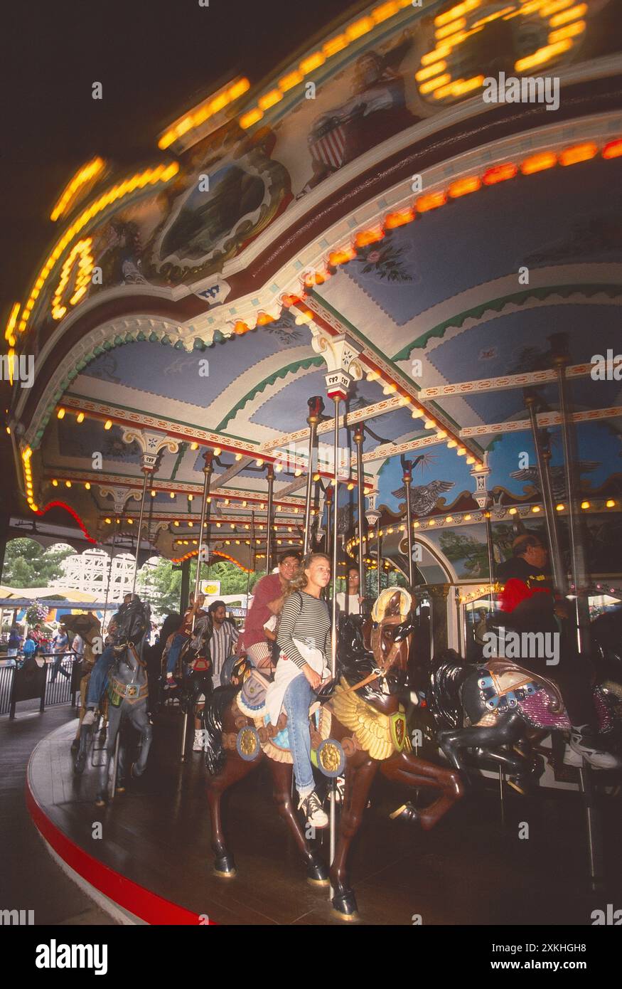 Visitors riding a wooden horse in a blur of motion on a carousel at ...